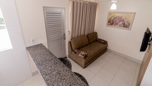 Sala de estar com sofá marrom, mesa de jantar e ventilador de teto.