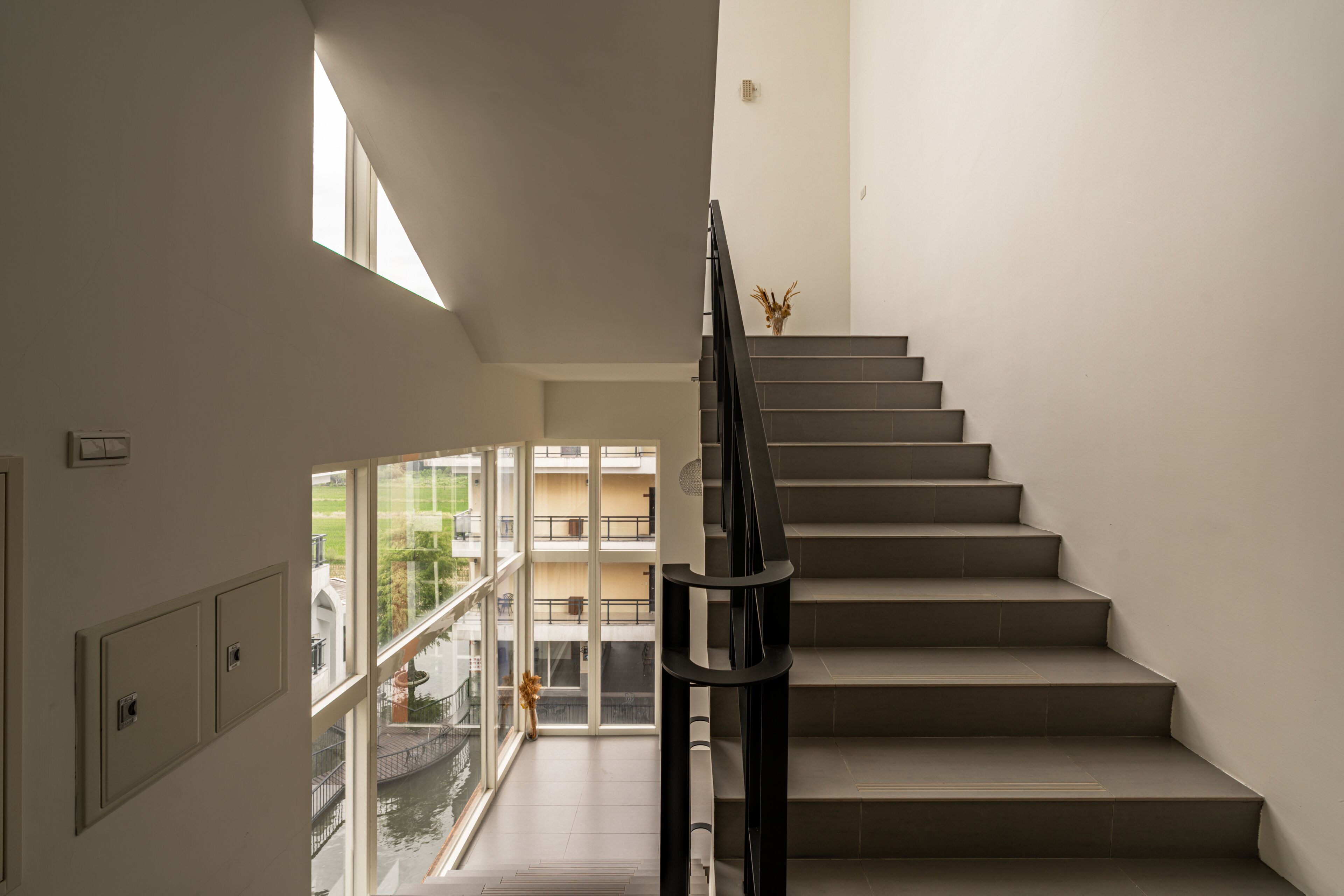 Uma escadaria com design moderno que dá acesso a um andar superior com grandes janelas.