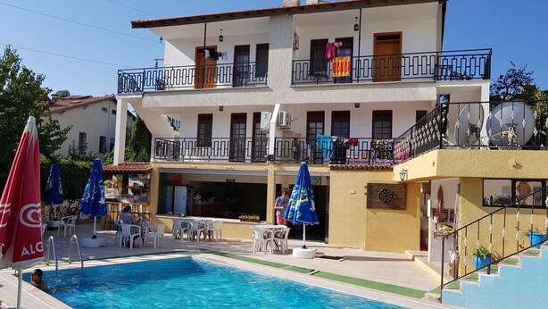 Um edifício de dois andares com piscina, área de estar ao ar livre e varandas.