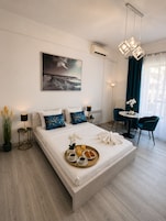 Quarto de hotel moderno com uma cama grande, área de refeições e vista para o exterior.