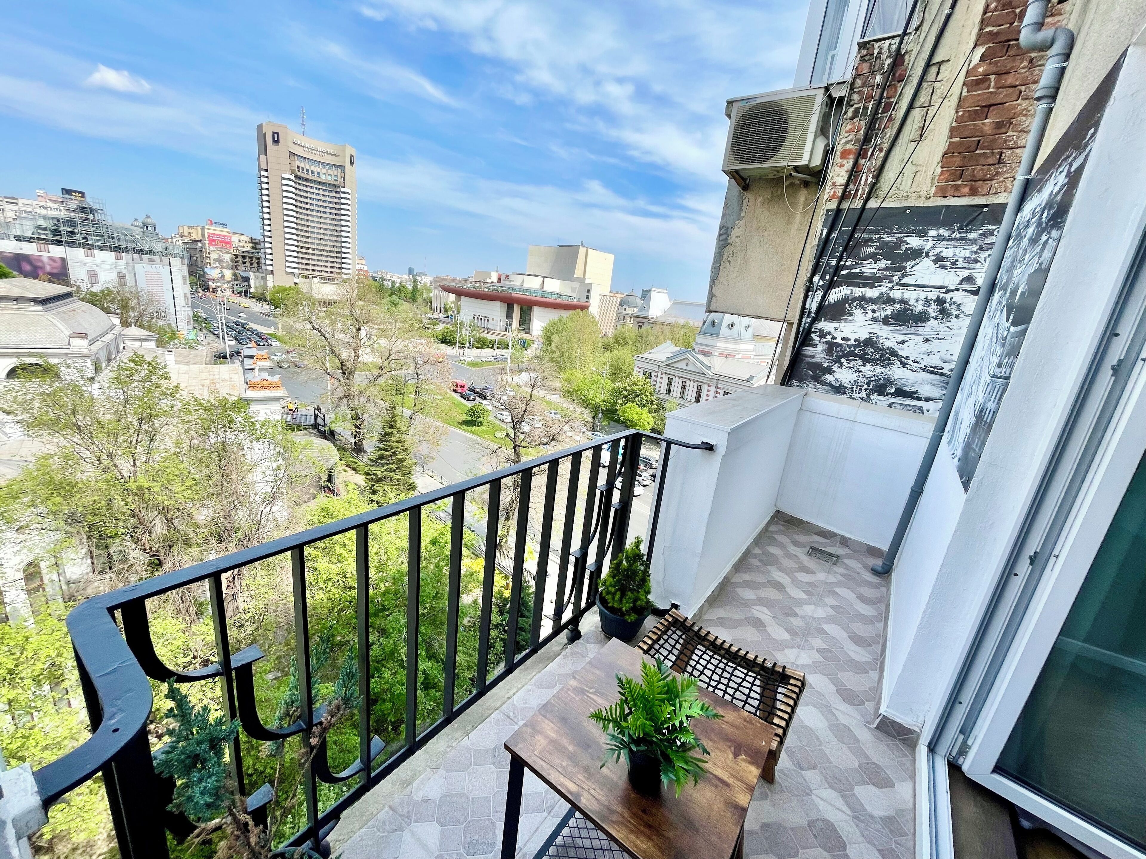 Uma varanda com vista para a paisagem urbana, incluindo edifícios e árvores.