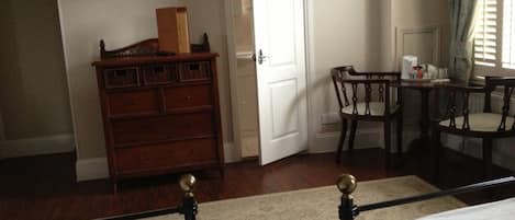 Quarto de hotel com duas camas, uma cômoda, uma televisão e um espaço de jantar com cadeiras e mesa.