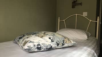 Uma cama de solteiro com cabeceira branca e almofada estampada com flores.