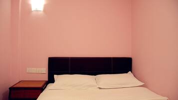Uma cama de solteiro com cabeceira de madeira em um quarto de paredes rosa.