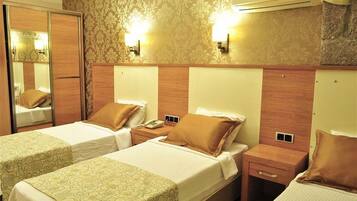 Quarto de hotel com duas camas, um espelho, um guarda-roupa e uma mesa de cabeceira com telefone.