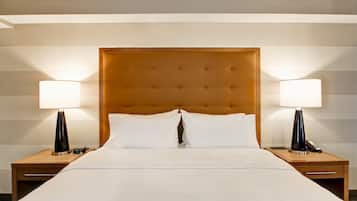 Quarto de hotel com uma cama grande, duas mesas de cabeceira e duas luminárias.