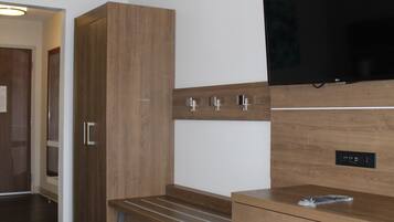 Quarto de hotel moderno com guarda-roupa de madeira, televisão de tela plana e escrivaninha com gavetas.