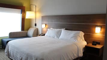 Quarto de hotel com uma cama grande, abajures, mesa de cabeceira e uma cadeira.