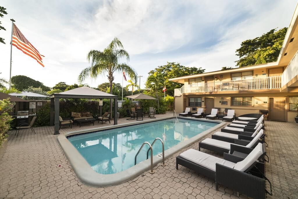 Piscina com espreguiçadeiras, área de estar coberta e uma bandeira americana.