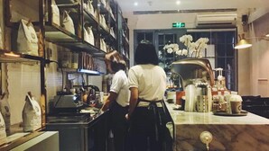 Uma cozinha com prateleiras cheias de embalagens, um balcão com diversos objetos e uma bancada de mármore.