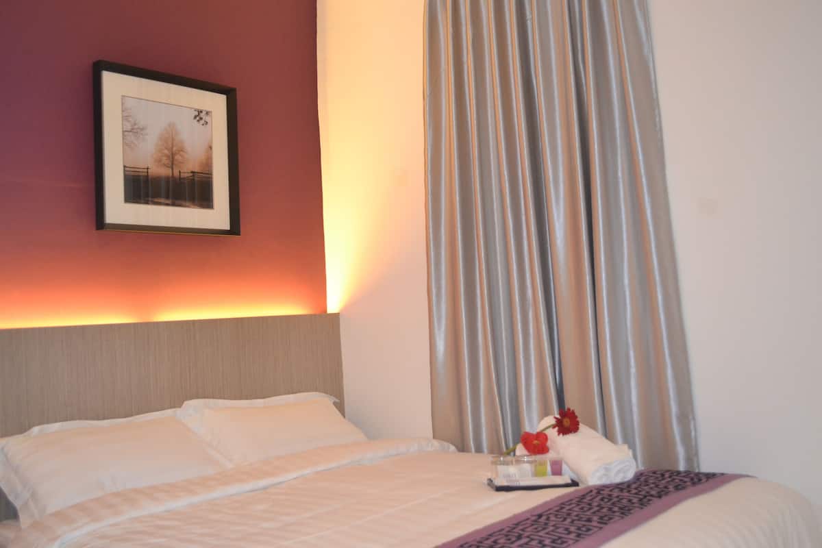 Quarto de hotel com uma cama, um quadro na parede e uma janela com cortinas.