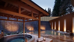 Uma área de spa com hidromassagem, deck de madeira e piso de pedra.