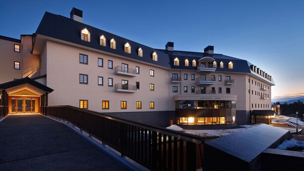 Um hotel grande com várias varandas e uma entrada bem iluminada.
