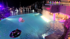 Piscina noturna com toboáguas e uma formação rochosa.