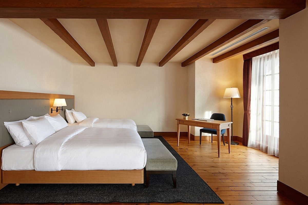 Quarto de hotel com uma cama grande, uma mesa e uma cadeira.