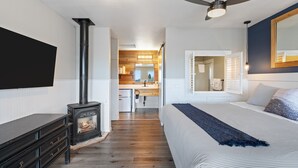 Quarto com cama, penteadeira, lareira e vista para a cozinha.