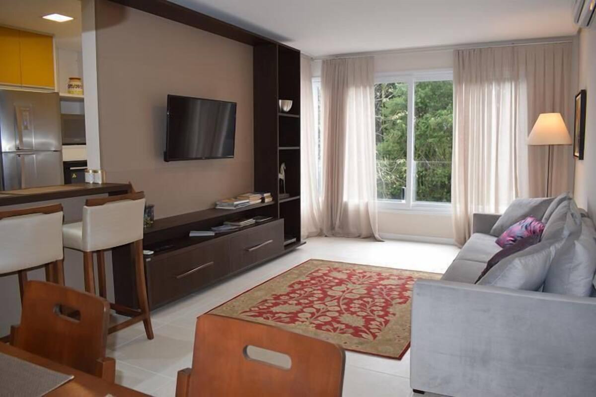 Uma sala de estar moderna com um sofá, uma mesa de centro e uma TV fixada na parede.