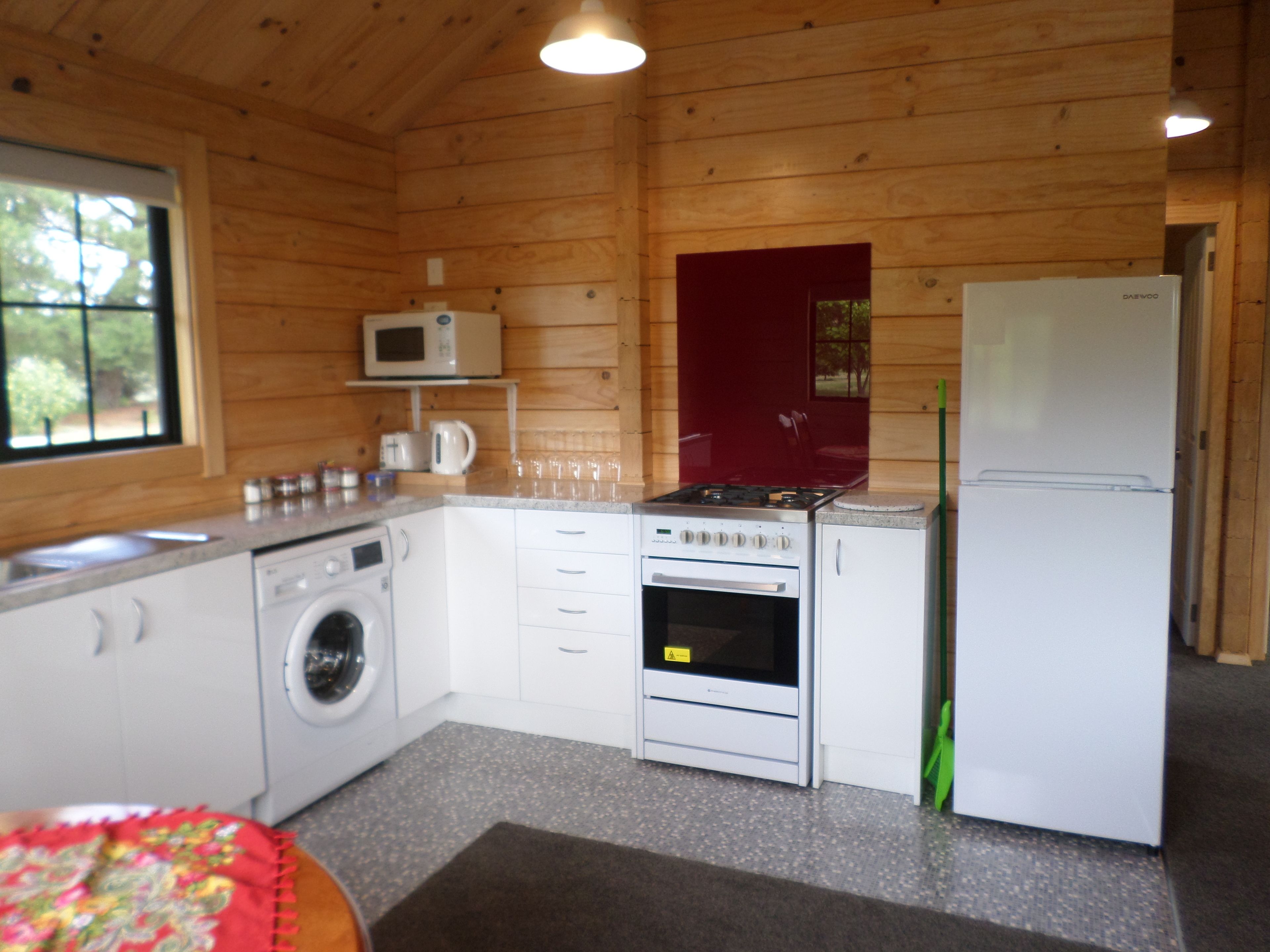 Cozinha compacta com máquina de lavar, micro-ondas, fogão, forno e frigorífico.