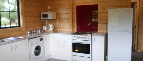 Cozinha compacta com máquina de lavar, micro-ondas, fogão, forno e frigorífico.
