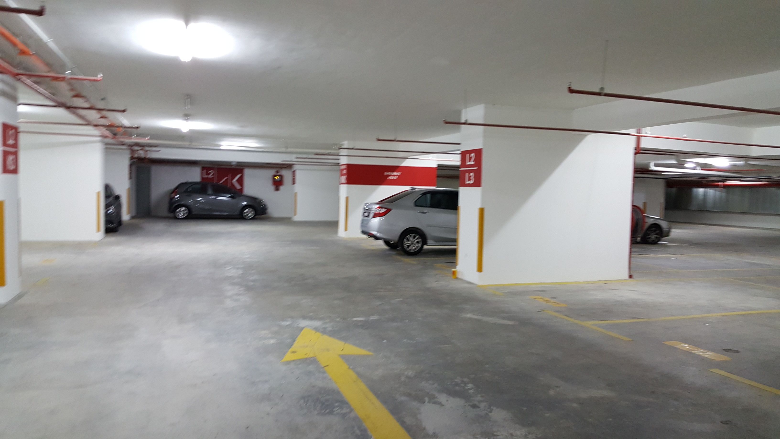 Um estacionamento subterrâneo com vários níveis e carros estacionados em vagas demarcadas.
