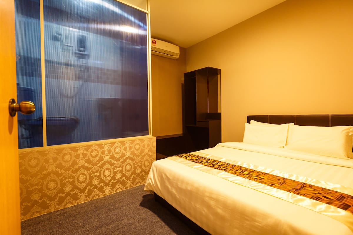Quarto de hotel com cama, guarda-roupa e ar condicionado.