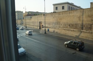 Rua com carros, faixa de pedestres e muro de tijolos.