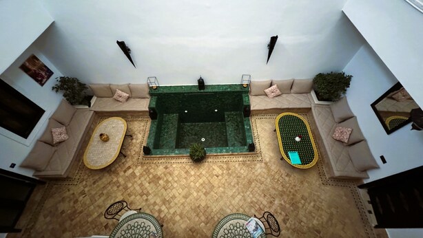 Um pátio interno com piscina central, áreas de estar e detalhes decorativos.