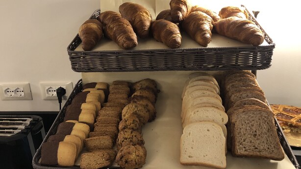 Vitrine de padaria com diversos produtos de panificação, incluindo croissants, biscoitos e pão.