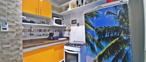 Cozinha equipada com micro-ondas, fogão e frigorífico com papel de parede tropical.