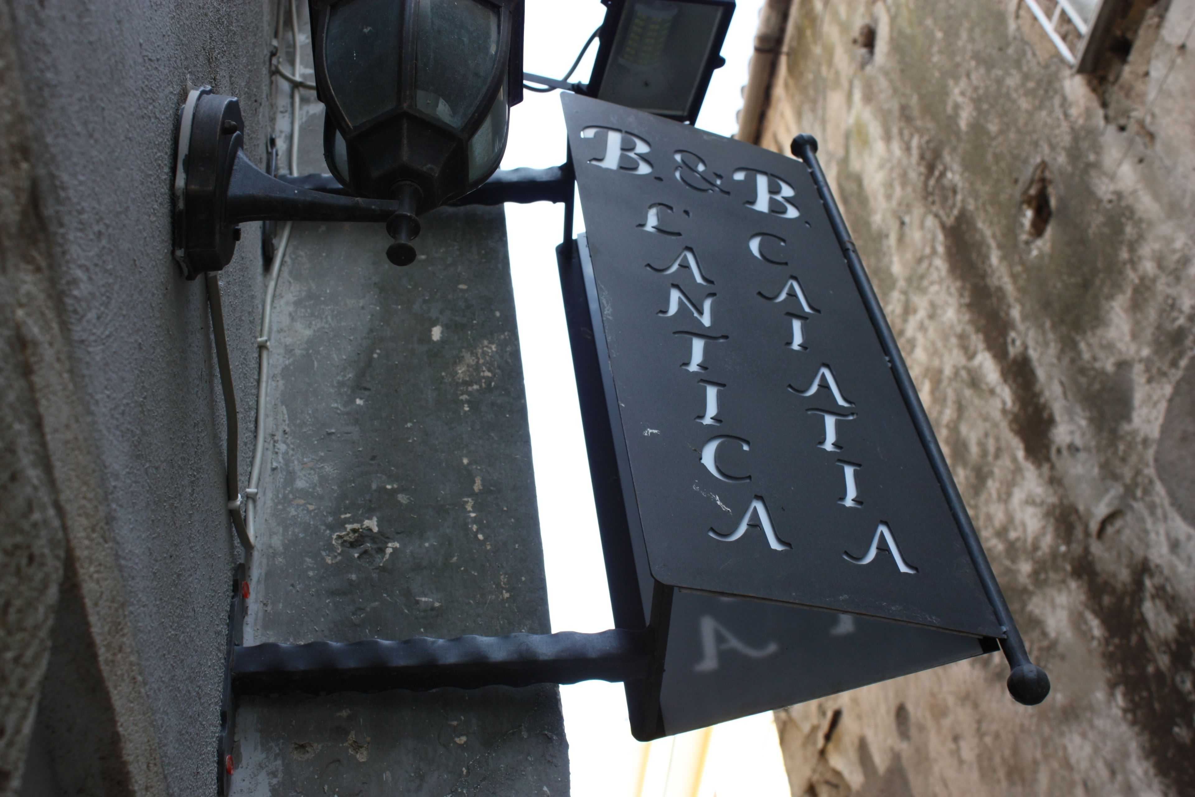 Uma placa de metal com a inscrição 'B&B CATALA L'ANTICA' fixada numa parede.
