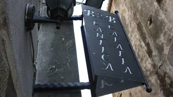 Uma placa de metal com a inscrição 'B&B CATALA L'ANTICA' fixada numa parede.