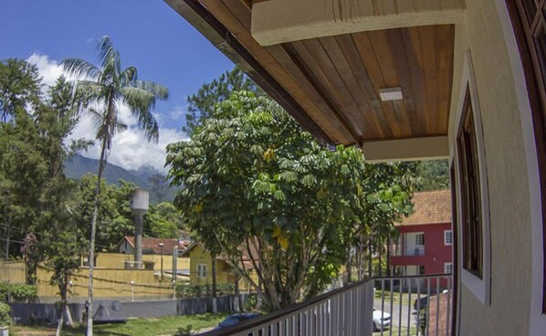 Uma área externa coberta com vista para um bairro residencial, incluindo casas e árvores.