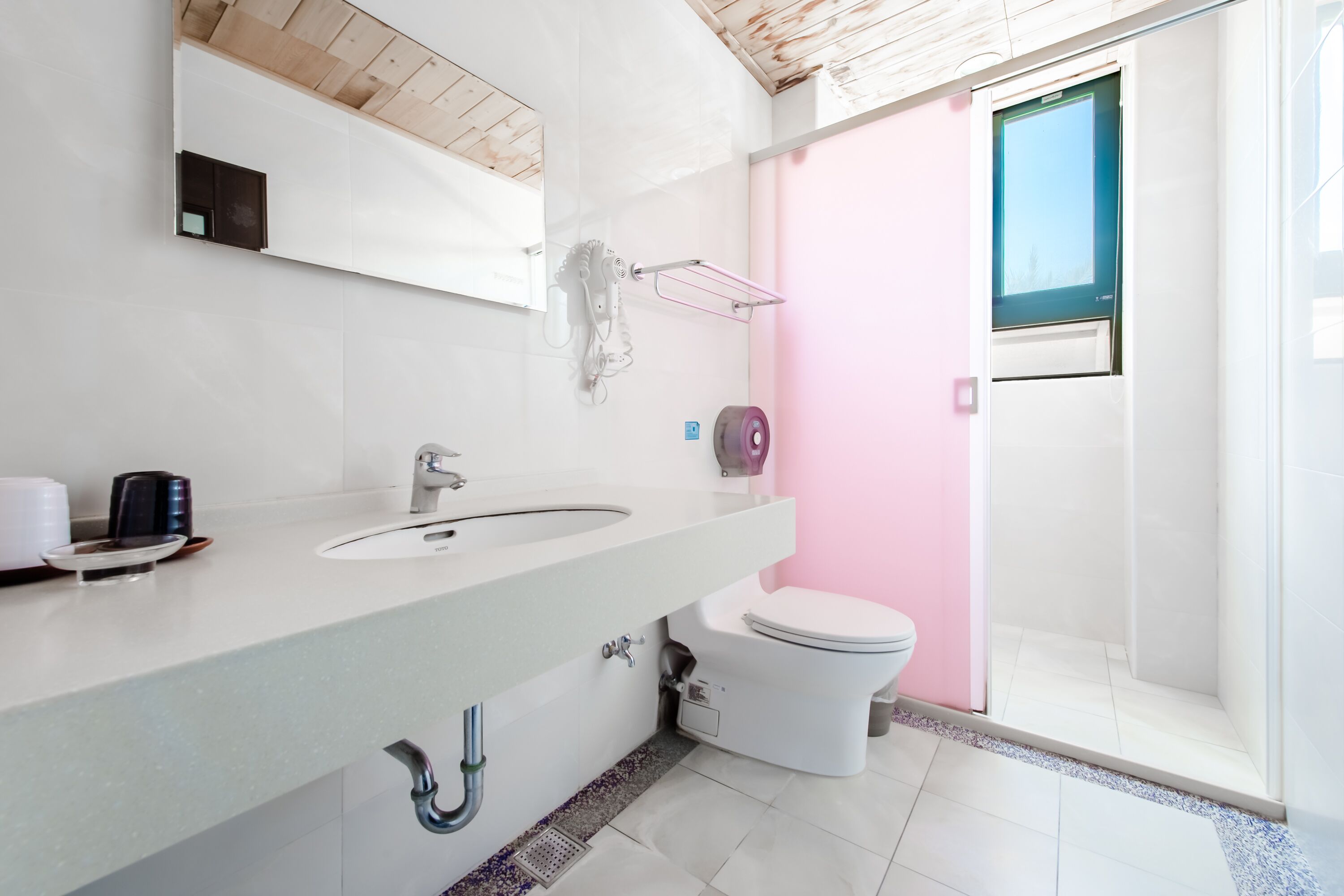Uma casa de banho moderna com lavatório branco, sanita e zona de duche.