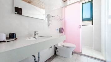 Uma casa de banho moderna com lavatório branco, sanita e zona de duche.