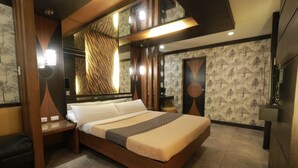 Quarto moderno com cama grande, cabeceira de madeira e espelho sobre a cama.