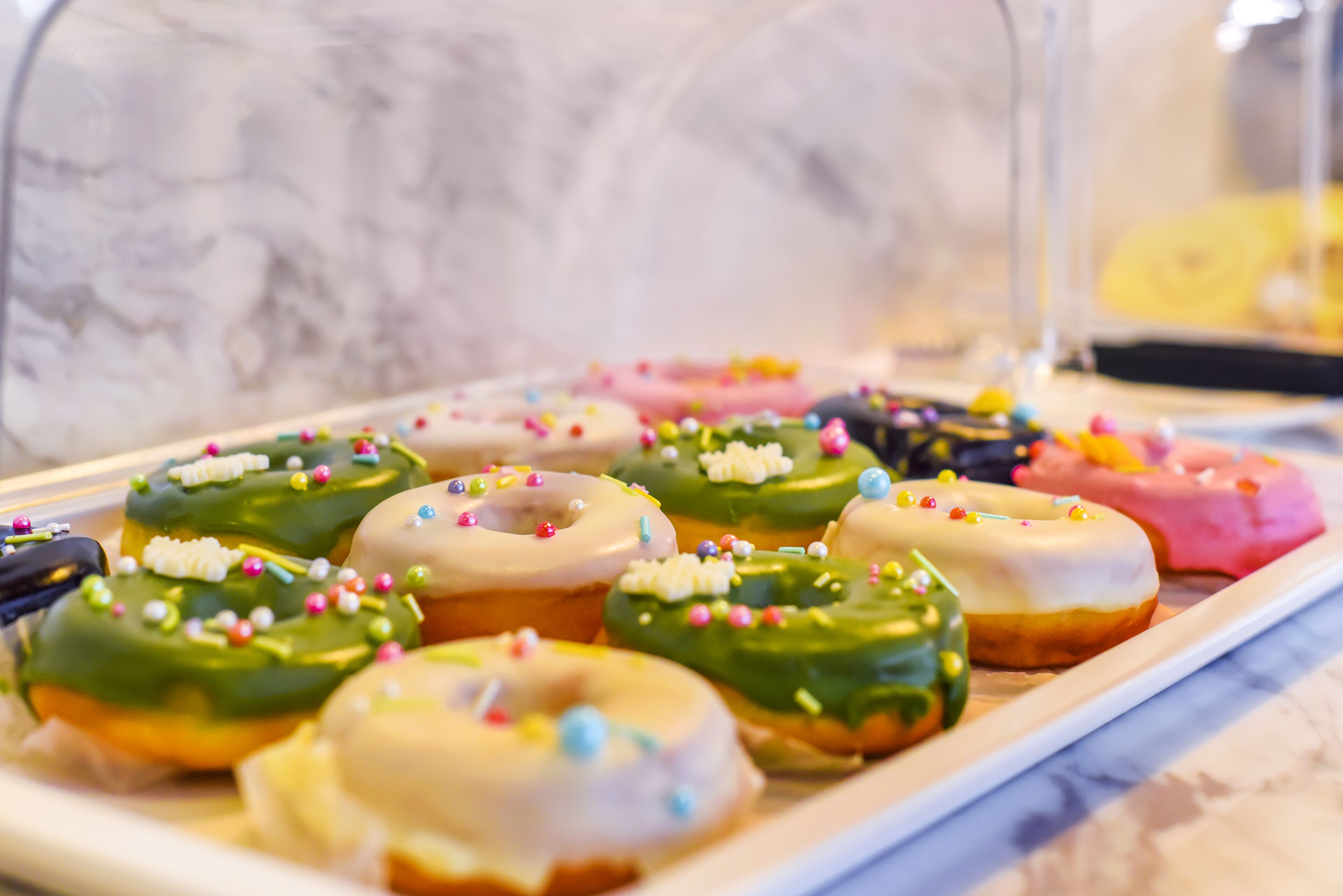 Uma bandeja com donuts variados, com diferentes coberturas e cores.