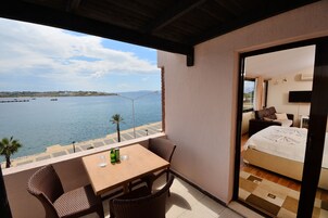 Uma varanda com móveis de vime, uma mesa e vista para o mar.