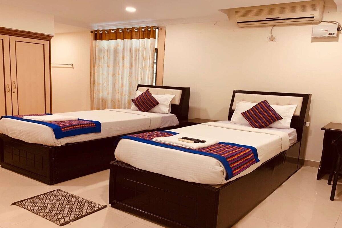 Quarto de hotel com duas camas, uma escrivaninha e um ar condicionado.