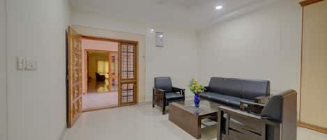 Uma sala de estar moderna com um sofá, duas poltronas, uma mesa de centro e um vaso decorativo.