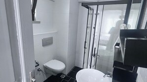 Uma casa de banho moderna com sanita, lavatório e cabine de duche em vidro.
