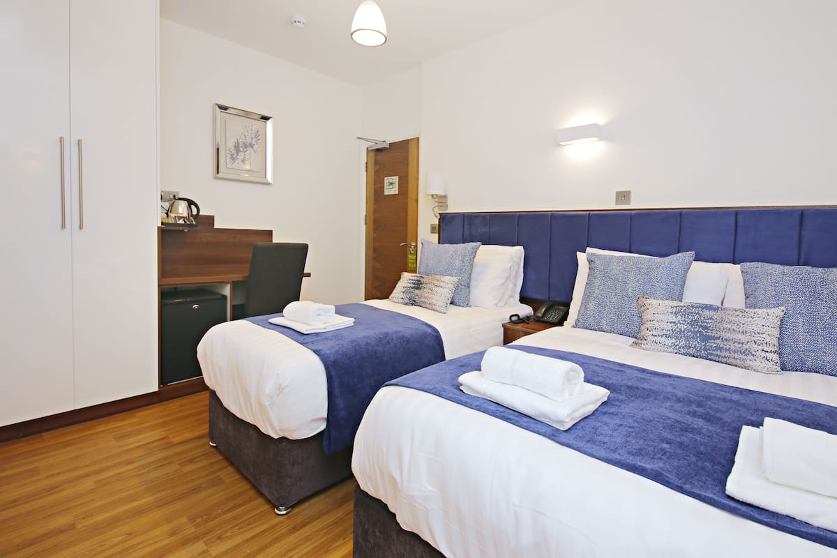 Quarto de hotel com duas camas, uma escrivaninha e uma cadeira.