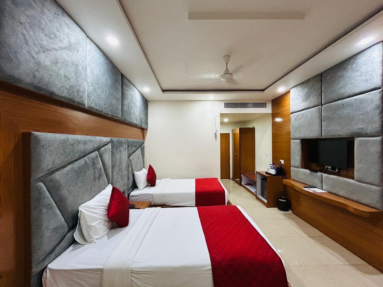 Quarto de hotel com duas camas, televisão e ventoinha no teto.