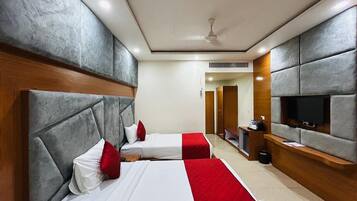 Quarto de hotel com duas camas, televisão e ventoinha no teto.
