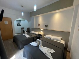 Quarto de hotel com duas camas, uma escrivaninha, uma cadeira e um espelho.