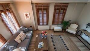 Uma sala de estar com sofá, poltronas, mesa de centro e planta em vaso.