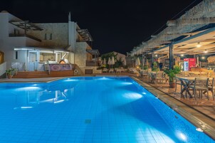 Piscina com fachada de pedra e área de estar externa.