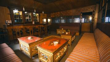 Quarto japonês tradicional com tatames, uma mesa de madeira baixa e um espaço bar com garrafas e copos.