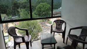 Varanda com mesa e quatro cadeiras, vista para área residencial com árvores e casas.