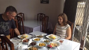 Uma mesa de jantar com diversos pratos, cadeiras e um pequeno vaso de flores.