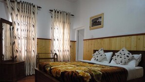 Quarto com cama de madeira, cortinas estampadas, cômoda de madeira e um quadro na parede.